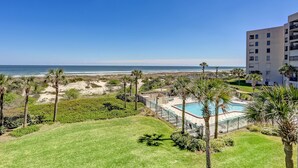 Um hotel com piscina, palmeiras e vista para a praia e o oceano.