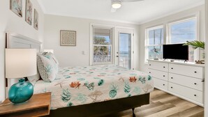 Quarto com cama, televisão, ventoinha no teto e janela com persianas.