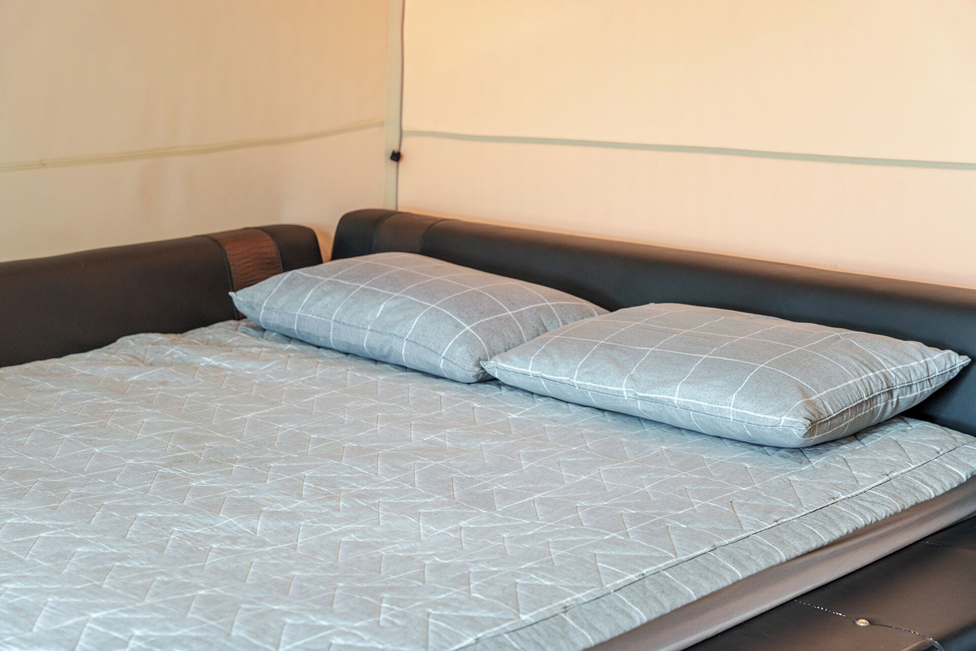 Uma cama com colchão acolchoado e duas almofadas.
