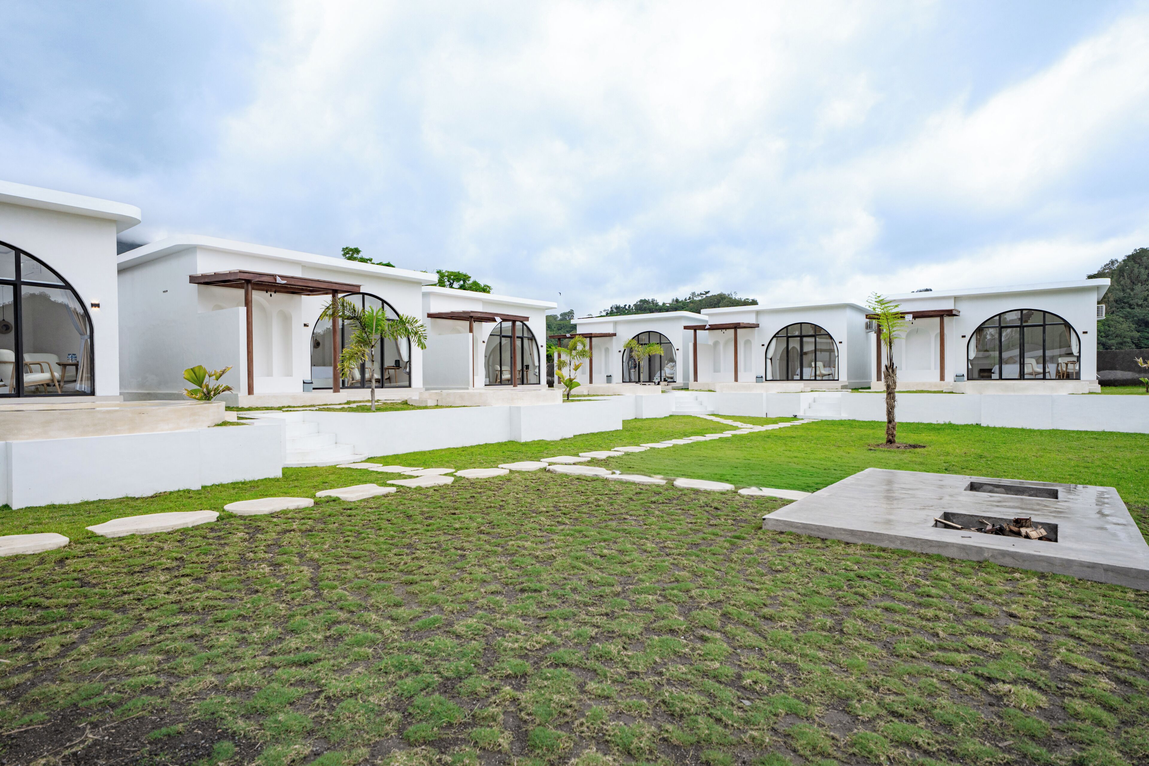Um complexo residencial moderno com várias casas brancas, cada uma com grandes janelas e um espaço de varanda coberto.