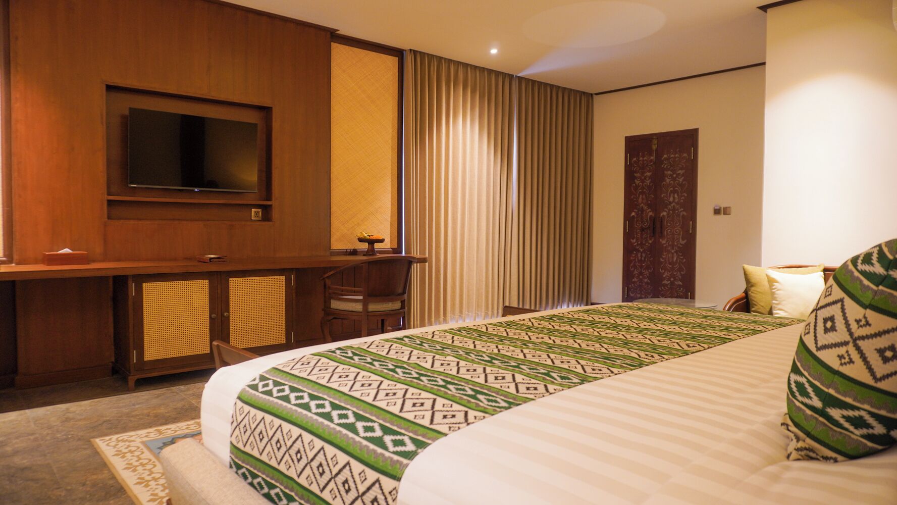 Quarto de hotel com uma cama, escrivaninha, televisão e armário.