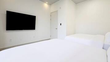 Quarto de hotel moderno com uma cama grande, televisão de tela plana na parede e uma porta.