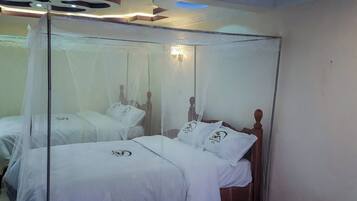 Quarto com duas camas, cada uma coberta com roupa de cama branca e um dossel.