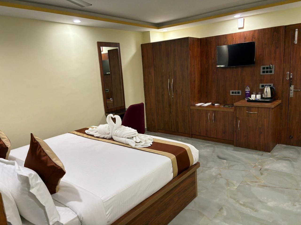 Quarto de hotel com uma cama grande, guarda-roupa de madeira, televisão de tela plana e minibar.