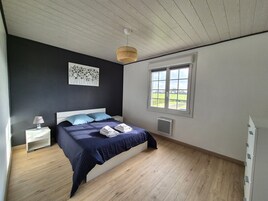 Quarto com cama, mesa de cabeceira, janela e ar-condicionado fixado na parede.