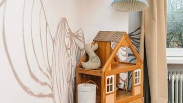 Quarto com casinha de madeira, um recipiente branco e parede com padrão de folhas.