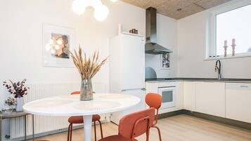 Uma cozinha moderna com uma mesa de jantar redonda, cadeiras vermelhas e teto branco.
