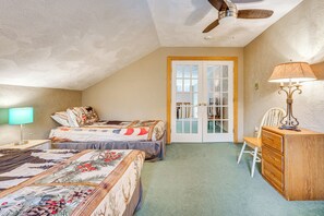 Quarto com duas camas, um ventilador de teto, uma cômoda e uma luminária.