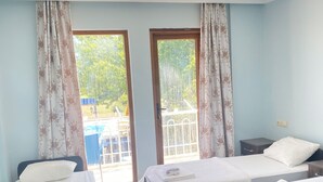 Quarto de hotel com duas camas, uma mesa e uma janela com cortinas.