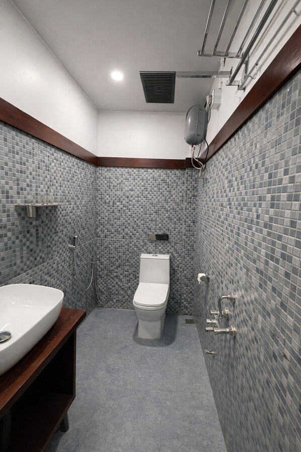 Uma casa de banho moderna com sanita branca, lavatório e chuveiro.