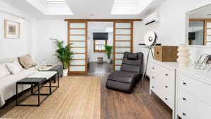 Uma sala de estar moderna com sofá, poltrona, mesa de centro, abajur e um espelho grande.