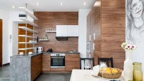 Uma cozinha moderna com armários de madeira, forno embutido e área de refeições com mesa posta para dois.