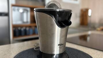 Uma cozinha com um centrífuga Philco Nectar Turbo PEF750 sobre um tapete preto.