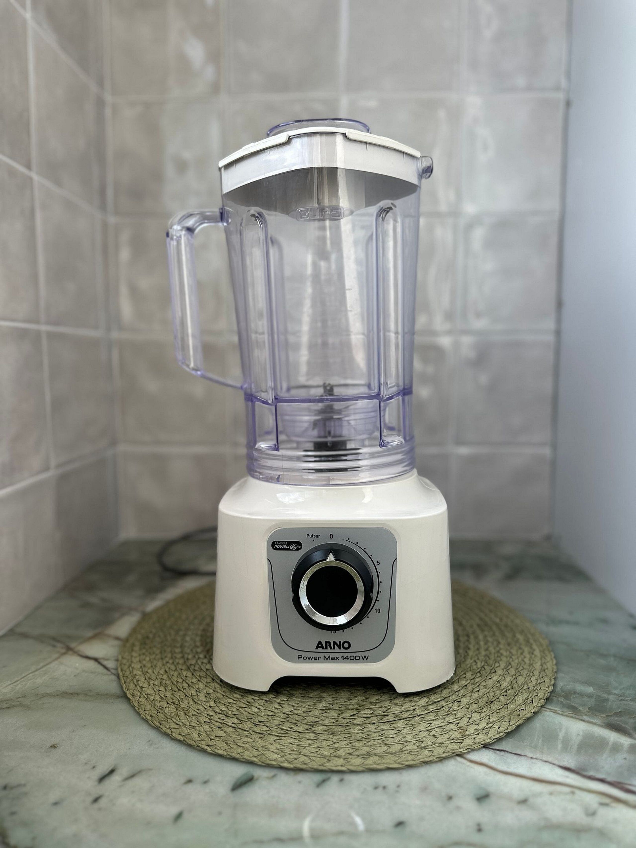 Uma cozinha com um liquidificador branco sobre um tapete trançado.