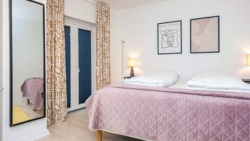 Um quarto com cama, espelho e obras de arte na parede.