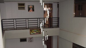 Um interior com vários níveis, varandas, luminária pendente e obras de arte nas paredes.
