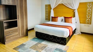 Quarto de hotel com cama, um guarda-roupa e cabeceira decorativa.