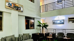 Uma sala de estar em vários níveis com piso de grama sintética verde, sofás cinzas, uma mesa de centro de madeira e poltronas pretas.
