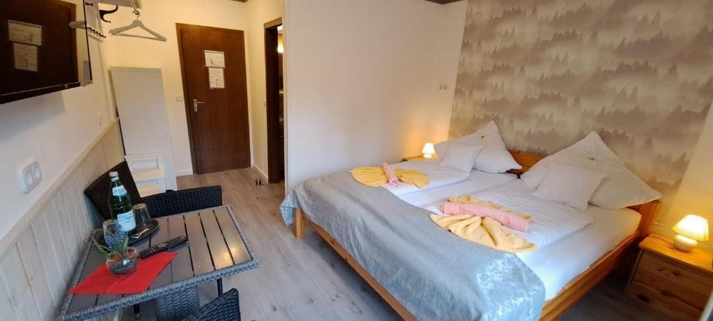 Um quarto com cama, mesa de cabeceira e uma cadeira.
