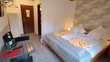 Um quarto com cama, mesa de cabeceira e uma cadeira.