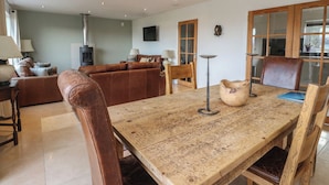 Uma sala de estar ampla com uma mesa de jantar de madeira, sofás de couro e uma lareira.