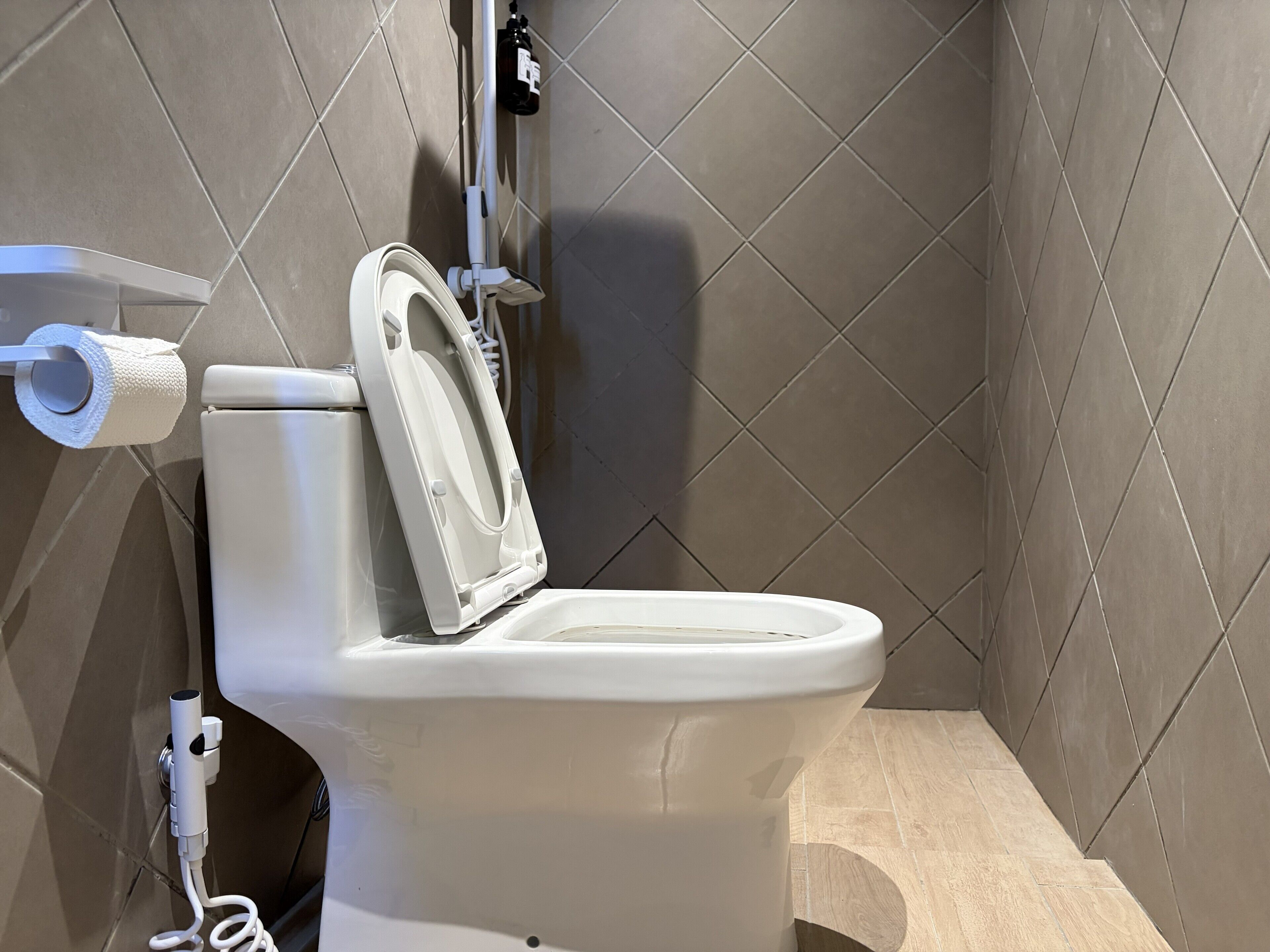 Uma casa de banho moderna com sanita, suporte para papel higiénico e secador de mãos.