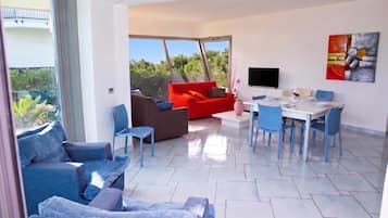 Uma sala de estar moderna com área de jantar, janelas amplas e televisão de tela plana.