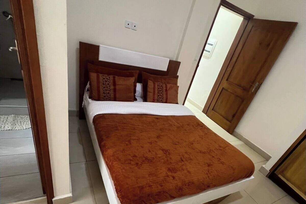 Quarto com cama, cabeceira de madeira e guarda-roupa.