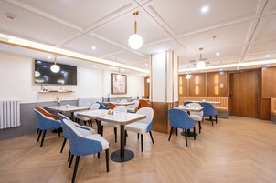 Uma sala de jantar moderna com mesas, cadeiras, uma TV de tela plana e iluminação pendente.