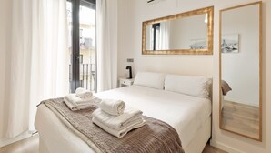 Quarto de hotel com cama, espelho grande, mesa de cabeceira e janela com cortinas.