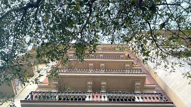 Um edifício de vários andares com detalhes arquitetônicos elaborados, incluindo colunas e molduras decorativas.