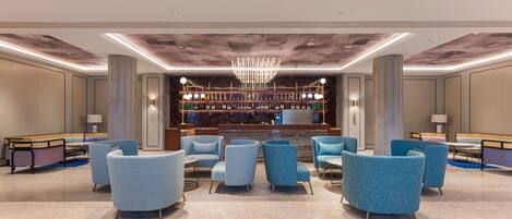 Um lobby com área de bar, assentos e um candelabro.