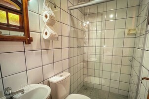 Uma casa de banho com chuveiro, sanita e lavatório.