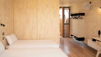 Quarto com parede de madeira, cama, escrivaninha com cadeira e um cabideiro.