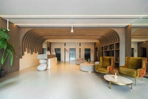 Um lobby moderno com balcão de recepção curvo, área de estar com poltronas e design minimalista.