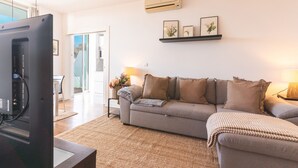 Uma sala de estar com sofá, TV, lareira e prateleira na parede com fotos.