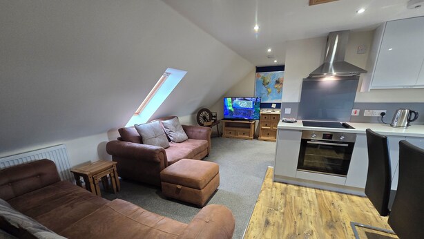 Um espaço de estar moderno estilo loft com cama mezanina, sofá, mesa de centro e cozinha equipada com fogão e forno.