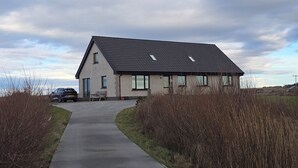 Uma casa térrea com telhado inclinado, entrada com calçamento e gramado.