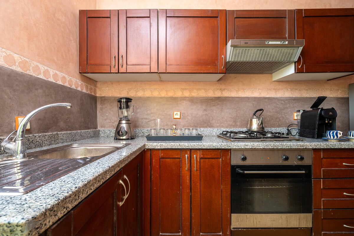 Uma cozinha com bancadas de granito, eletrodomésticos de aço inoxidável, armários de madeira e forno embutido.