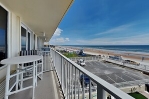 Uma varanda com vista para a praia, área de estacionamento e mobiliário para áreas externas.
