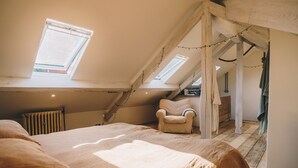 Quarto com uma cama grande, uma cadeira e um claraboia.