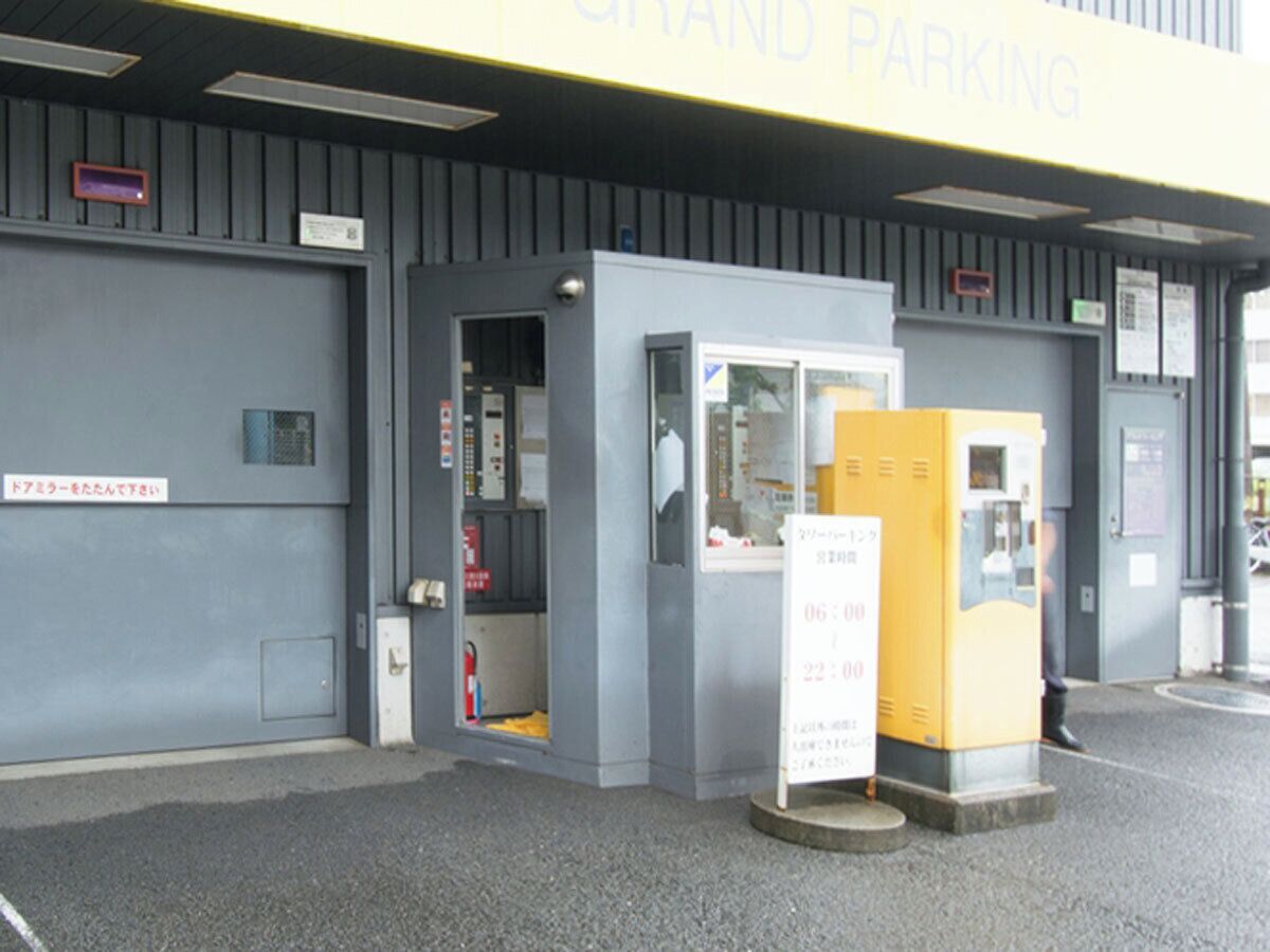 Entrada de um estacionamento com uma placa indicando 'GRAND PARKING' e um painel de exibição digital.