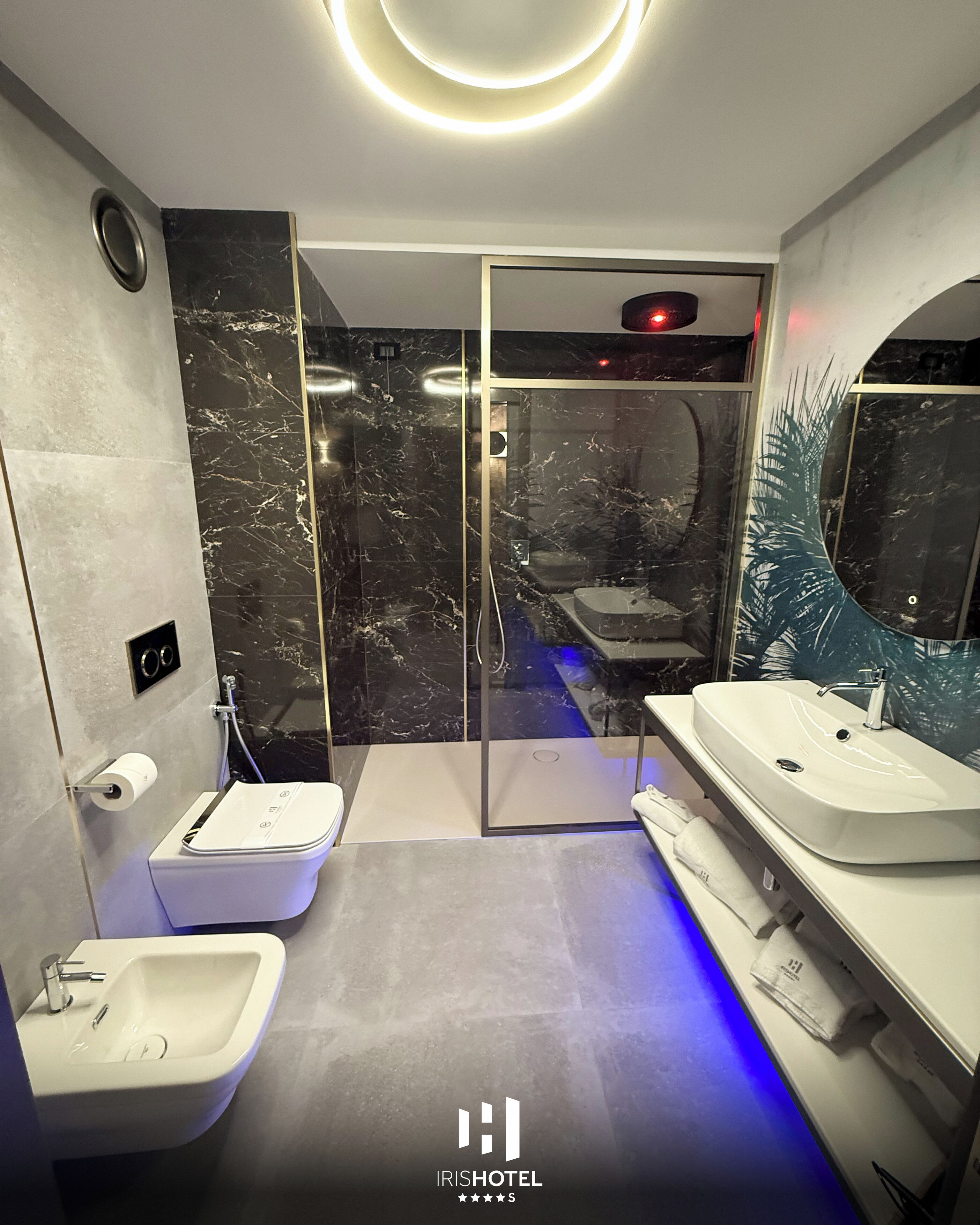 Uma casa de banho moderna com chuveiro em cabine de vidro, duas pias e sanita.