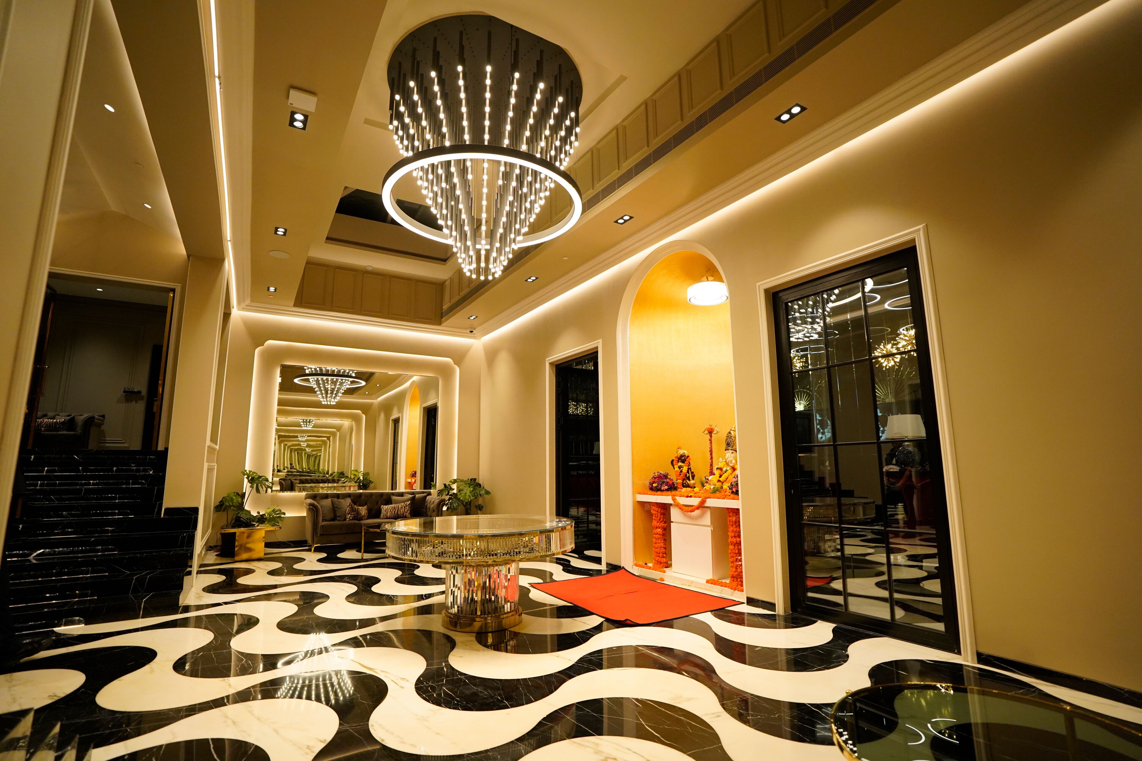 Um hall de hotel com design moderno, destacando um grande lustre, piso estampado e um balcão de recepção.