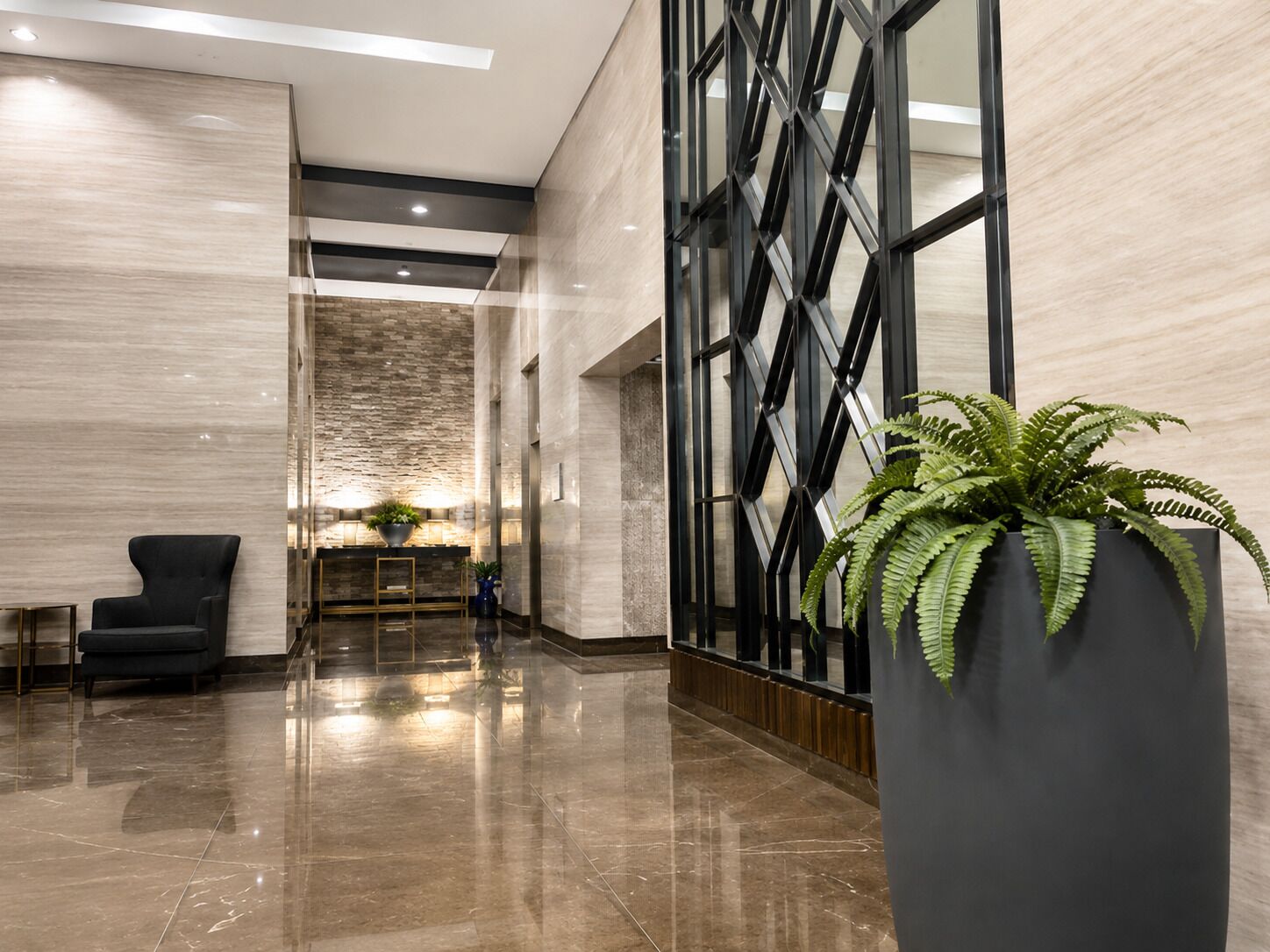 Um hall moderno com piso de mármore, balcão de recepção, área de estar e uma grande planta em vaso.
