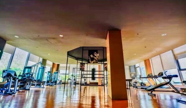 Uma academia com equipamentos de exercício, janelas amplas e um pilar central.
