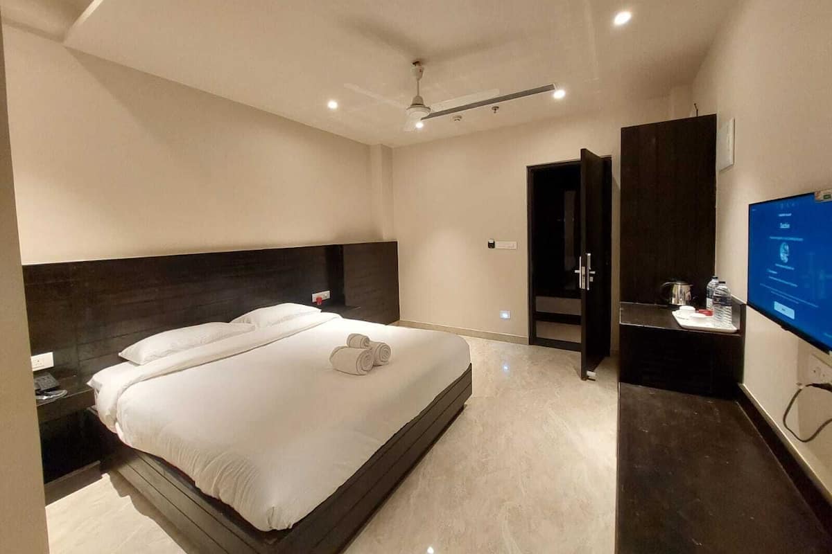 Quarto de hotel moderno com uma cama grande, televisão de tela plana, escrivaninha com cadeira e armário.