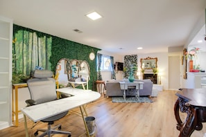 Uma sala de estar moderna com um mural verde, uma área de jantar com mesa branca e um espaço de estar aconchegante com lareira.