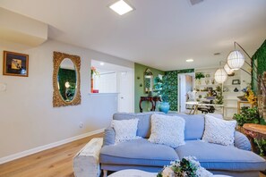Uma sala de estar com um sofá azul, um espelho e uma parede verde.