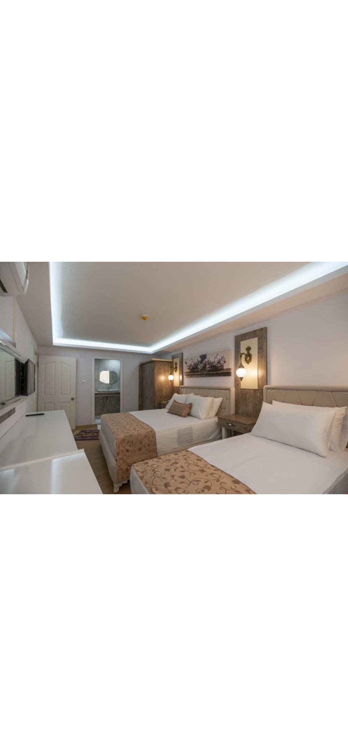 Quarto de hotel com duas camas, uma escrivaninha e uma pequena cozinha.